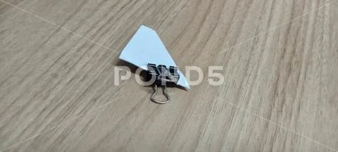 Black Paper Clip clamps paper on wood grain table background. ~ Premium ...