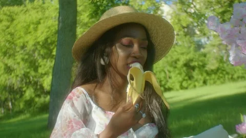 Black Woman calmly eating banana in park... | Stock Video | Pond5