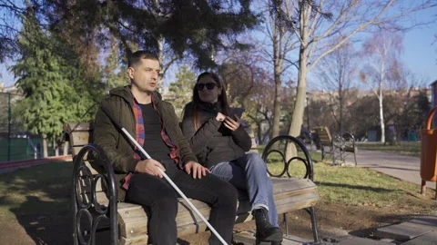Blind man sitting on park bench chatting... | Stock Video | Pond5