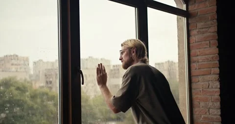 Blond-haired man looks out the window Wh... | Stock Video | Pond5
