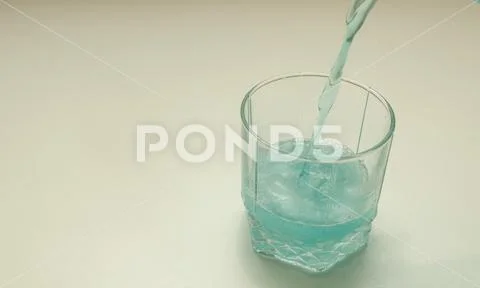 Blue ale with bubbles and ice. Pouring the drink in the glass. Bright ...