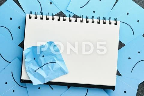 Blue crumpled sticky notes blank with drawing sad face on black ...