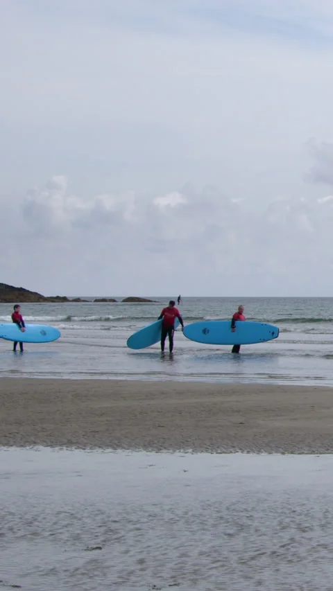 With blue surfboards in hand, surfers pa... | Stock Video | Pond5