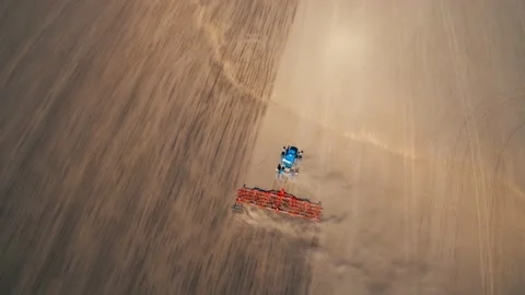 A blue tractor with a red plow loosens t... | Stock Video | Pond5