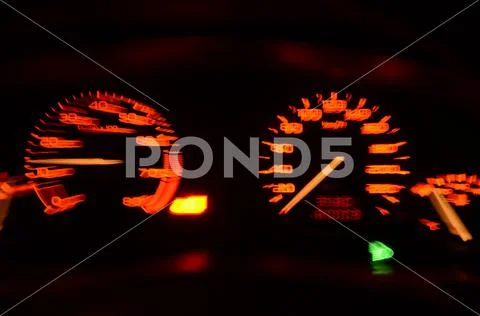 Blurred car speedometer during driving. Illuminated dashboard ...