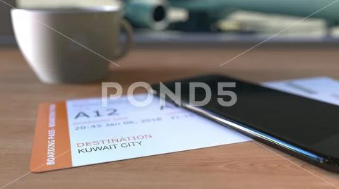 Boarding pass to Kuwait City and smartphone on the table in airport ...