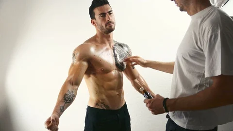 Bodybuilder getting oiled by assistant | Stock Video | Pond5