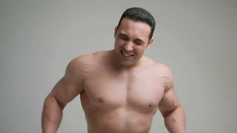 Bodybuilder shows strong biceps on a whi... | Stock Video | Pond5