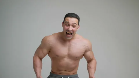 Bodybuilder shows strong biceps on a whi... | Stock Video | Pond5