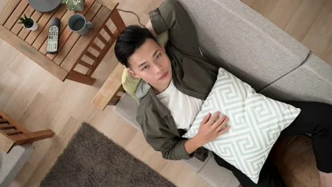 bored asian man lying on sofa is tapping... | Stock Video | Pond5
