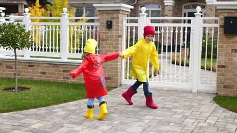 A boy and a girl in raincoats and boots ... | Stock Video | Pond5