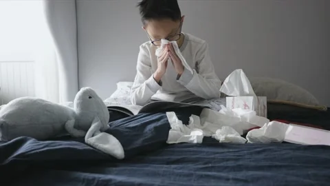 Boy with cold reading book and blowing n... | Stock Video | Pond5