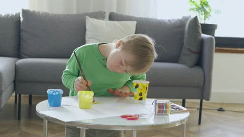Boy with Down Syndrome drawing at home | Stock Video | Pond5