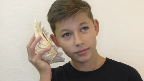 The boy lifted the sea shell to his ear ... | Stock Video | Pond5
