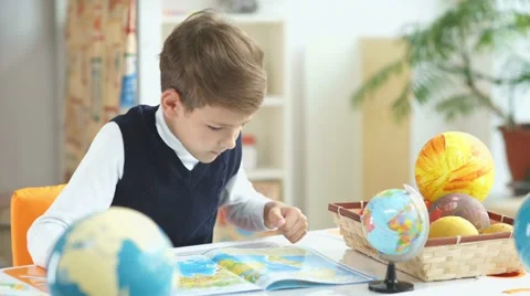 The boy looks atlas with maps. Schoolboy... | Stock Video | Pond5