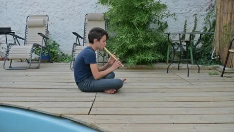 Boy playing flute outdoors on a wooden d... | Stock Video | Pond5