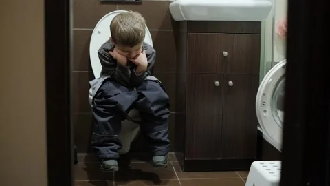 a boy sits on the toilet in the restroom | Stock Video | Pond5