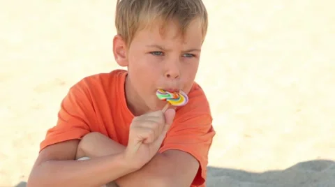 The boy sitting on the sand and eating c... | Stock Video | Pond5