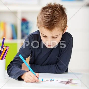 Boy using colored pencil while drawing on paper at table ~ Hi Res #26254598