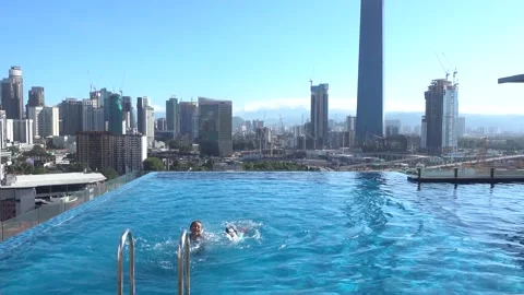 Boys swimming in infinity pool with city... | Stock Video | Pond5