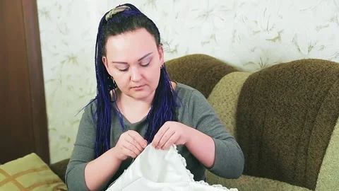 A bride with blue braids on a sofa sews ... | Stock Video | Pond5