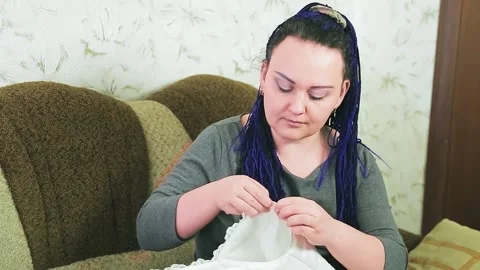 A bride with blue braids on a sofa sews ... | Stock Video | Pond5