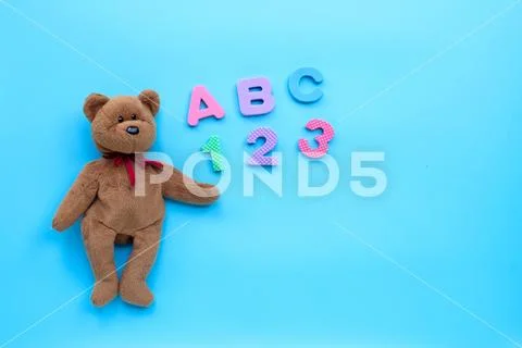 Photograph: Brown bear toy with english alphabet and numerals on blue ...