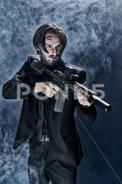 Brutal man with automatic gun in his hands in the night on smoky ...