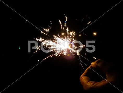 Photograph: Burning of hand held sparkle firework in black background ...