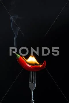 Photograph: Burning hot red pepper on fork. Black background #60707432