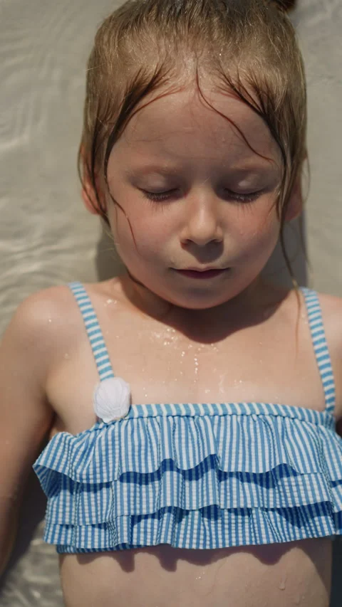 Calm little girl lies in clear shallow p... | Stock Video | Pond5