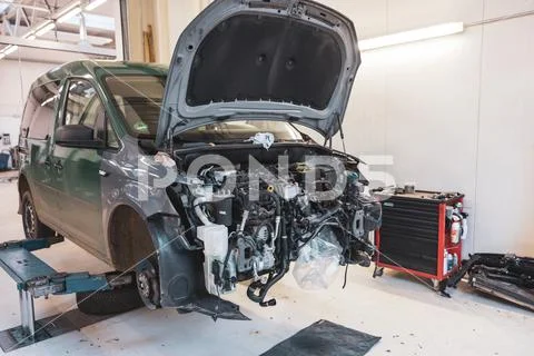 A car without the front and without the hood is standing in a garage ...