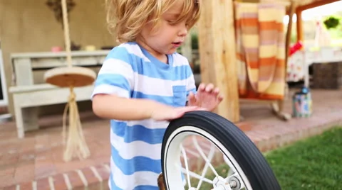Caucasian boy spinning tricycle wheel, | Stock Video | Pond5