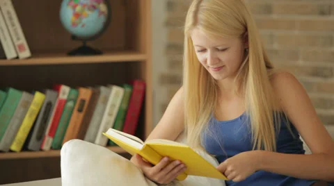 Charming girl sitting on sofa reading bo... | Stock Video | Pond5