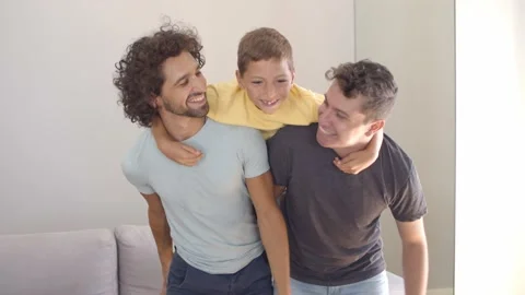 Cheerful boy and his two fathers enjoyin... | Stock Video | Pond5