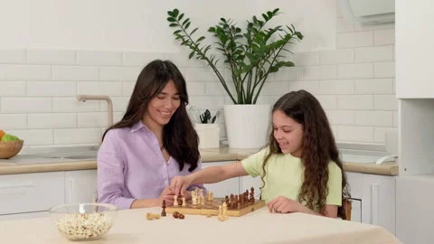 Cheerful daughter wins mom in chess whil... | Stock Video | Pond5