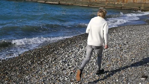 Cheerful man running on pebble beach and... | Stock Video | Pond5