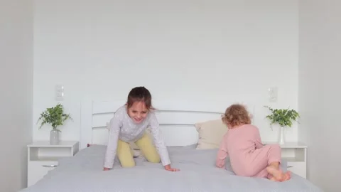 Cheerful overjoyed kids jumping bed in t... | Stock Video | Pond5