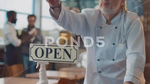 Photograph: Chef cleaning window and turning open sign board on glass ...