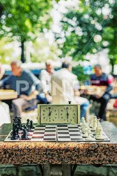 Chess board with pieces and clock on wooden desk In connection with the ...