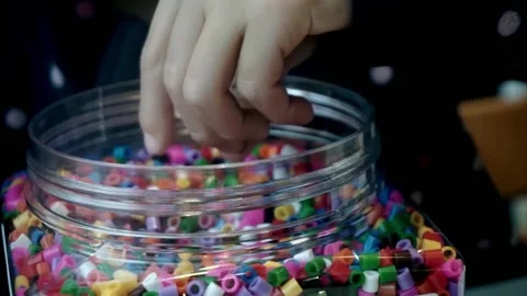 Child choosing perler beads from a jar | Stock Video | Pond5