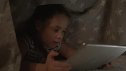 Child in dark room under covers looks at... | Stock Video | Pond5