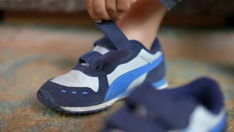 Child on doorstep putting shoes by himse... | Stock Video | Pond5