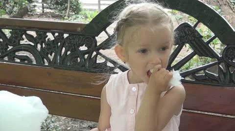 Child Eating Cotton Candy on a Bench in ... | Stock Video | Pond5