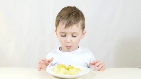 A child is eating potato chips from a pl... | Stock Video | Pond5