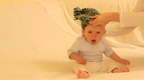 Child with green fez on sofa | Stock Video | Pond5