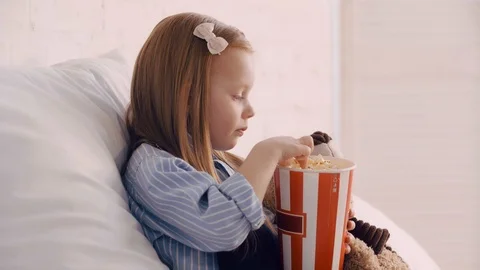 Child with popcorn and teddy bear on bed | Stock Video | Pond5