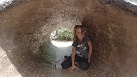 Child Sitting In A Hole Of A Tree Trunk | Stock Video | Pond5