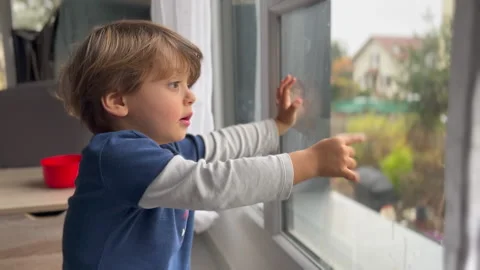 Child sitting by window home pointing ou... | Stock Video | Pond5
