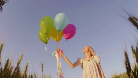Child spinning with balloons at wheat fi... | Stock Video | Pond5